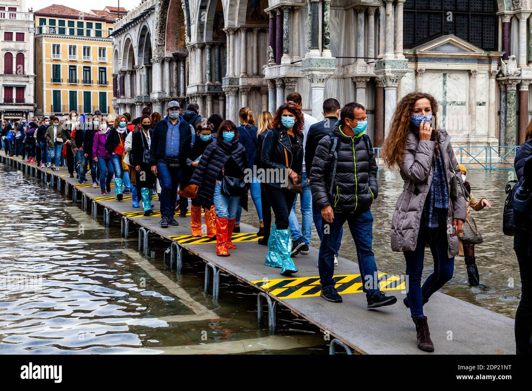 tourists walking on a raised platform during acqua alta high tide st marks square venice italy 2 ...